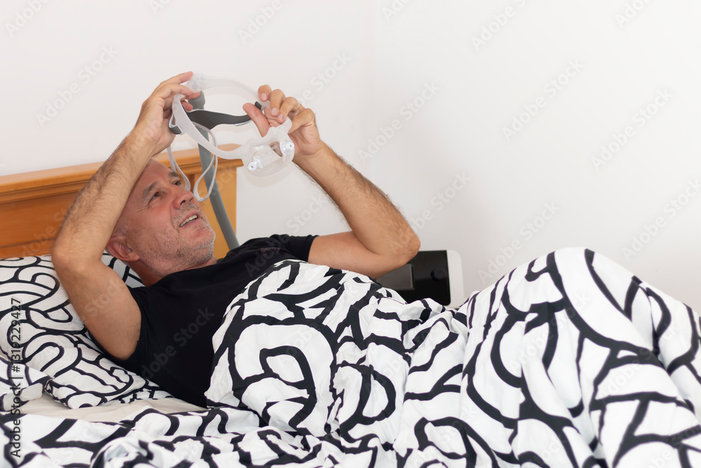 Poster A mature man adjusting a CPAP mask before going to sleep – Wall ...