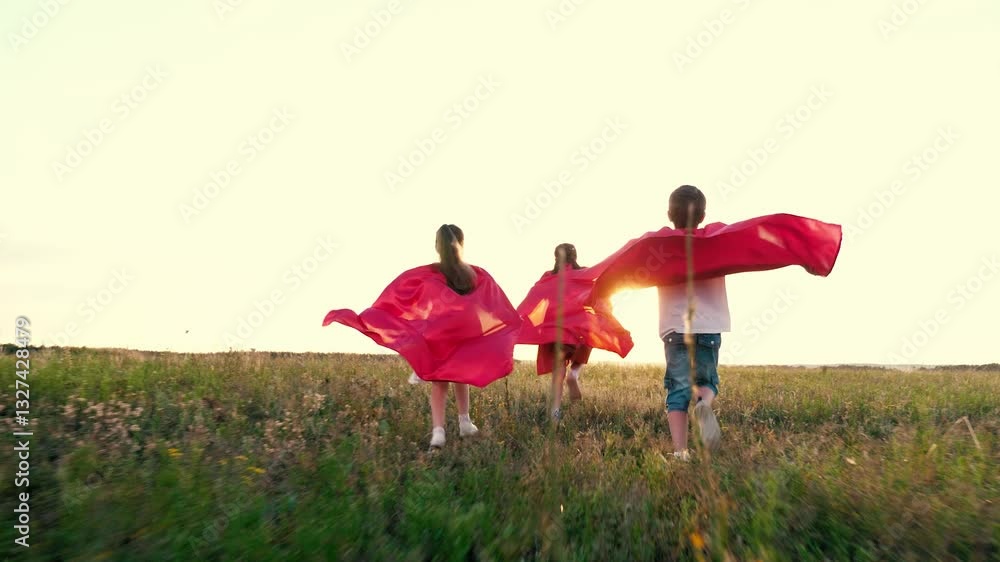 Little children wearing red capes play superheroes running across ...