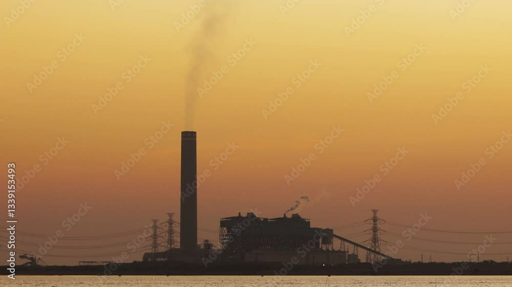 Stockvideon Smokestack emits smoke from power plant, silhouetted ...