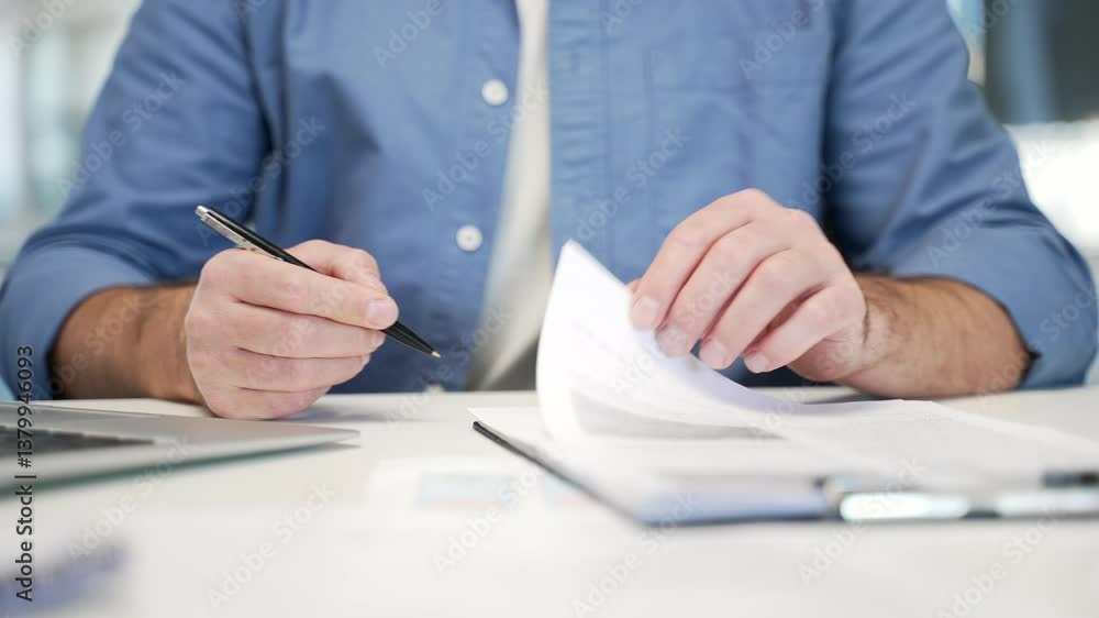 Close up of a male's hand signing documents at a desk at a workplace in ...