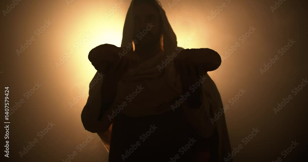 Silhouette of Jesus Christ in white hooded robe praying with bread as ...