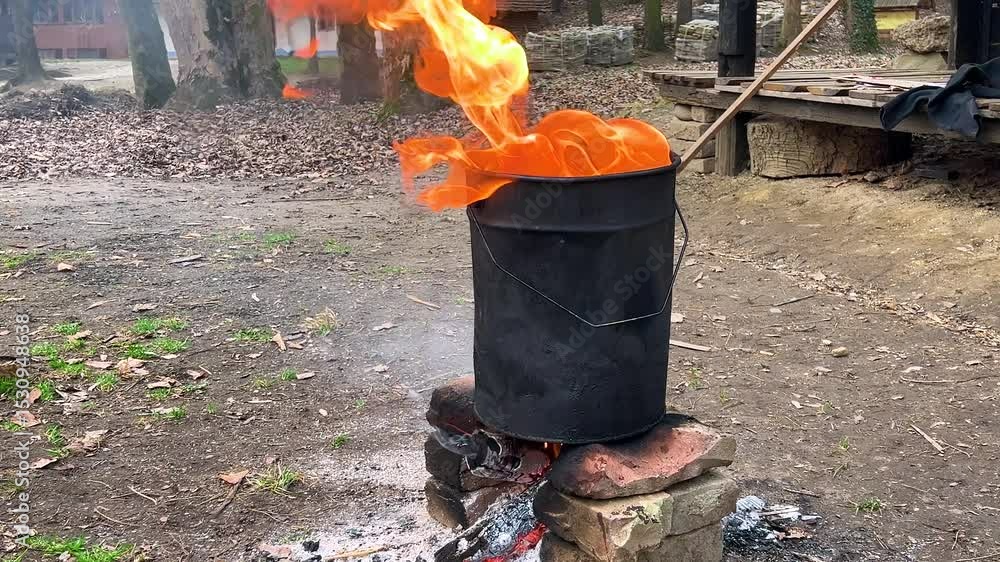 Crude oil is melted in an iron barrel over a fire to treat wooden ...