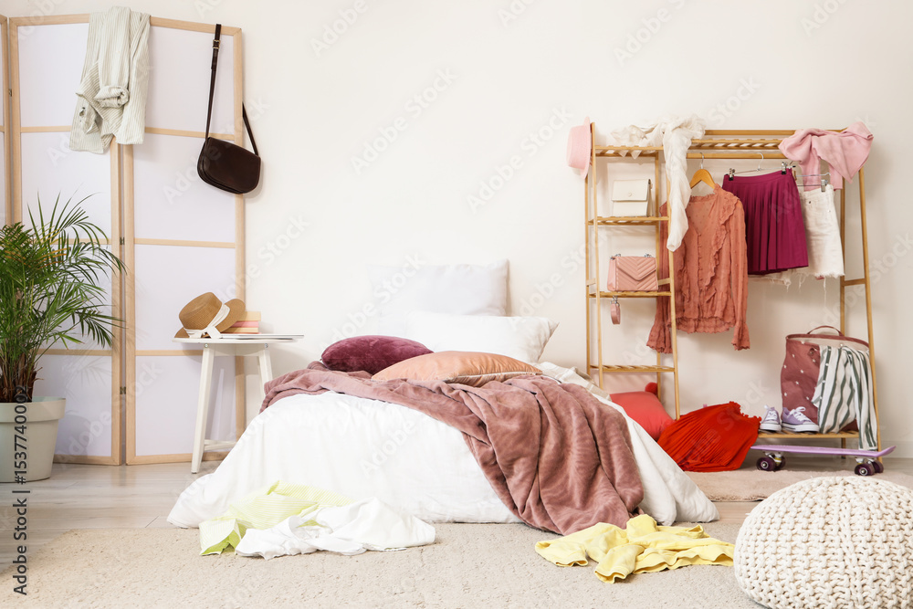 Poster Interior of messy children's room with bed, clothes rack and ...