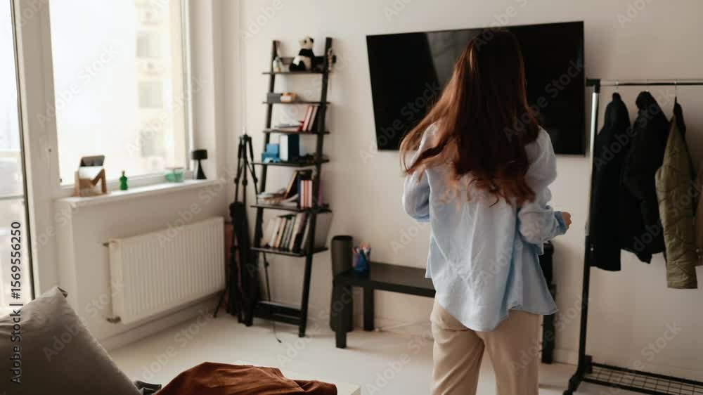 A woman takes off her jacket and throws it on the sofa, then chooses ...