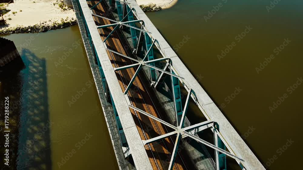 Railway bridge running above river with massive steel beams and brown ...