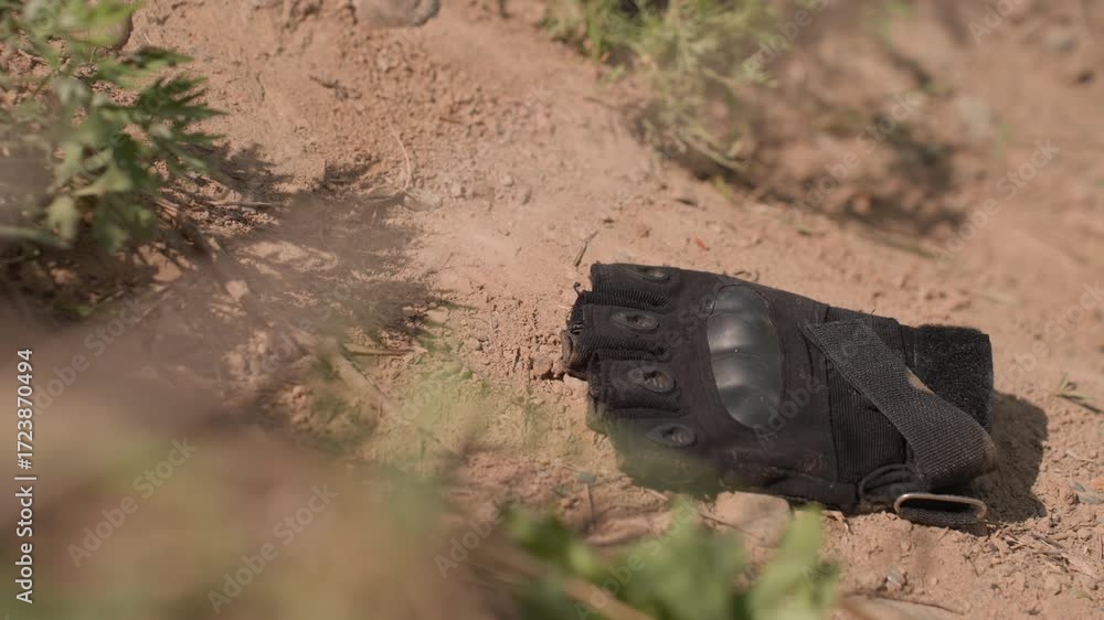 ground view of dirt path near riverbank with fingerless tactical glove ...