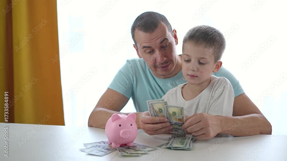 Boy looks at dollar bills while father teaches value of saving. Banking ...