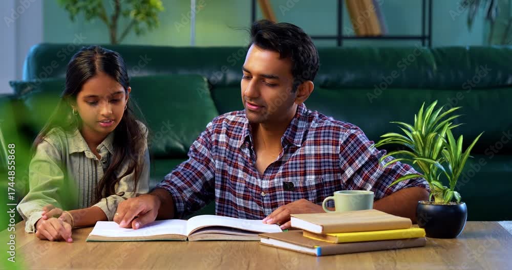 Teaching daughter from a text book, Indian young father helping child ...