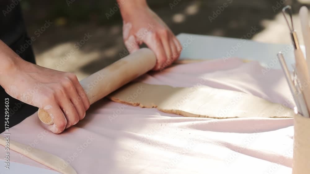 Rolling pin flattening clay on table 4k video. Clay is rolled flat with ...