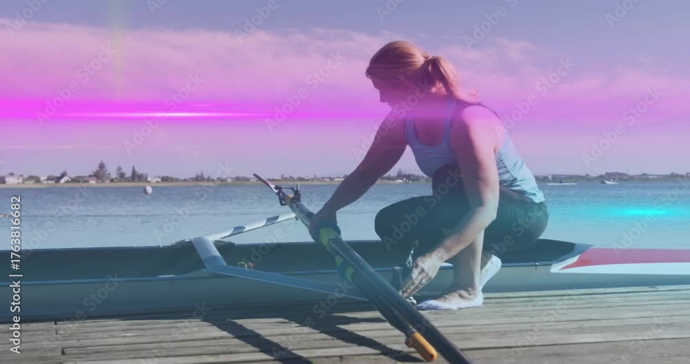 Stepping onto wooden dock, mature rowing athlete kneeling and adjusting ...