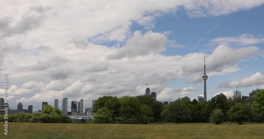 Toronto skyline rising behind an empty green park field and scattered ...