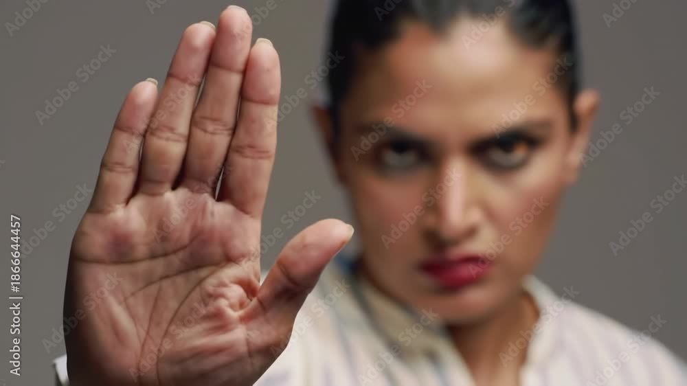 Close up portrait of a woman raising her hand in a stop gesture, with a ...