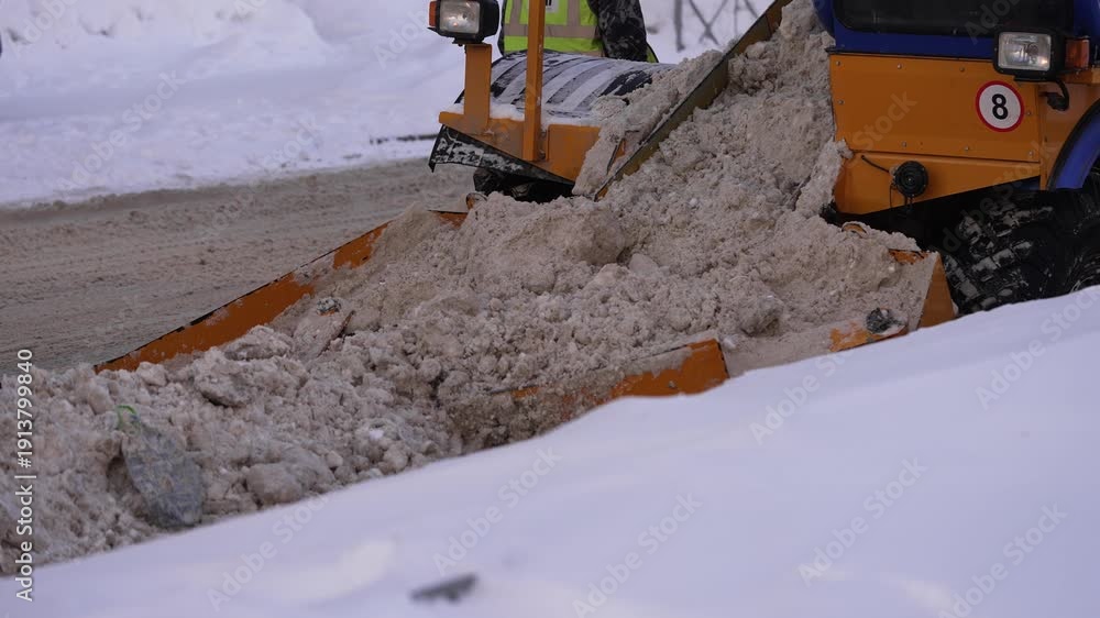 Orange municipal snowplow clearing dirty slush and ice from a city ...