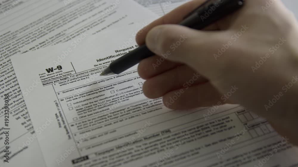 Person filling out a W-9 form. Request for Taxpayer Identification ...