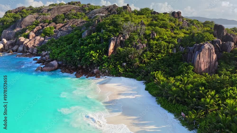 Turquoise ocean waves wash the white sand beach in the Seychelles ...
