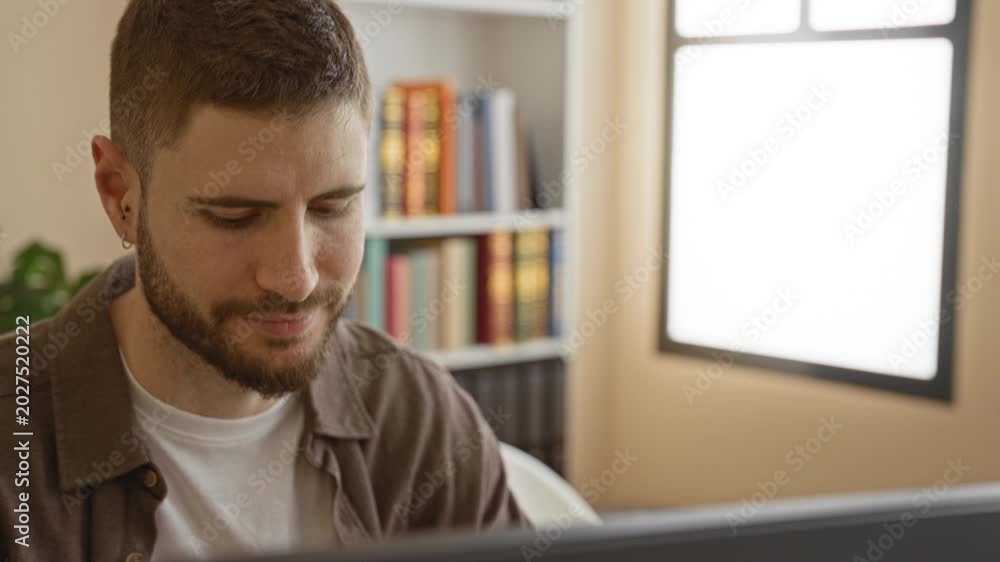 Man smiling at computer monitor, head turned toward screen in a ...