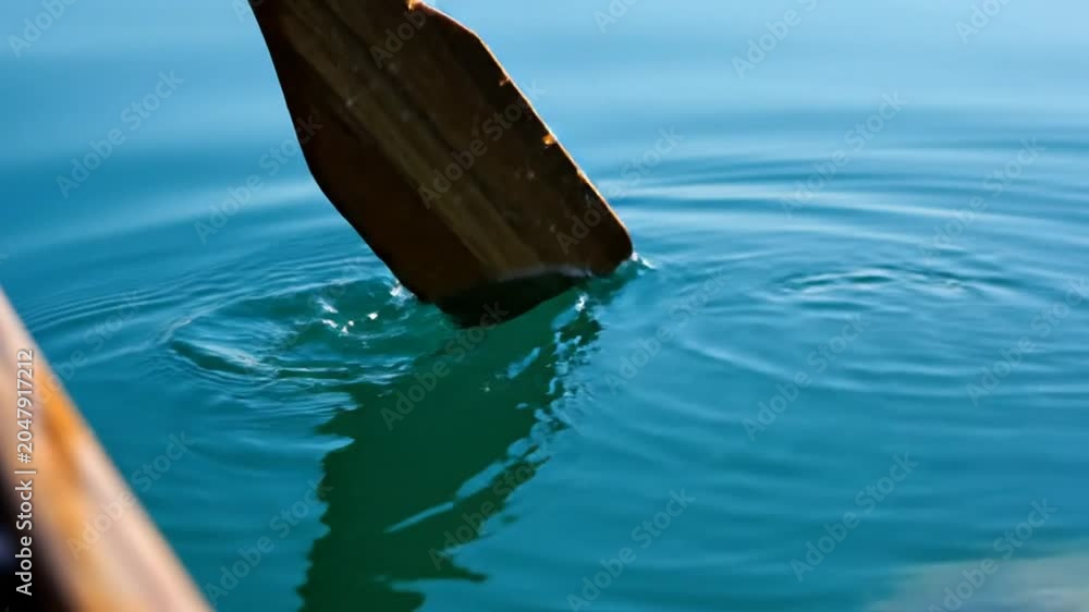 Close up shot of wooden oar in crystal blue water on a bright sunny day ...