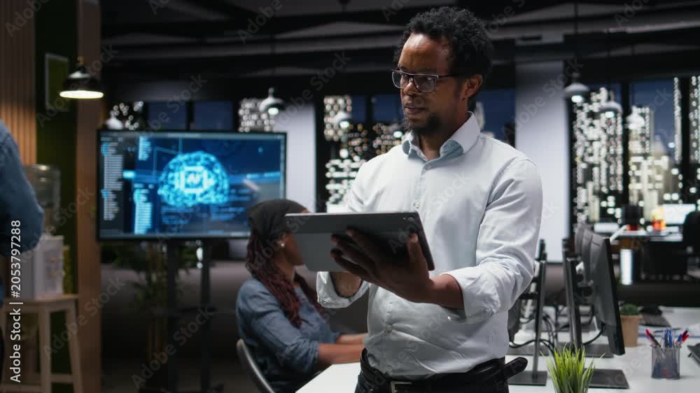 Engineer in office using tablet, working to fix bugs in AI system. IT ...
